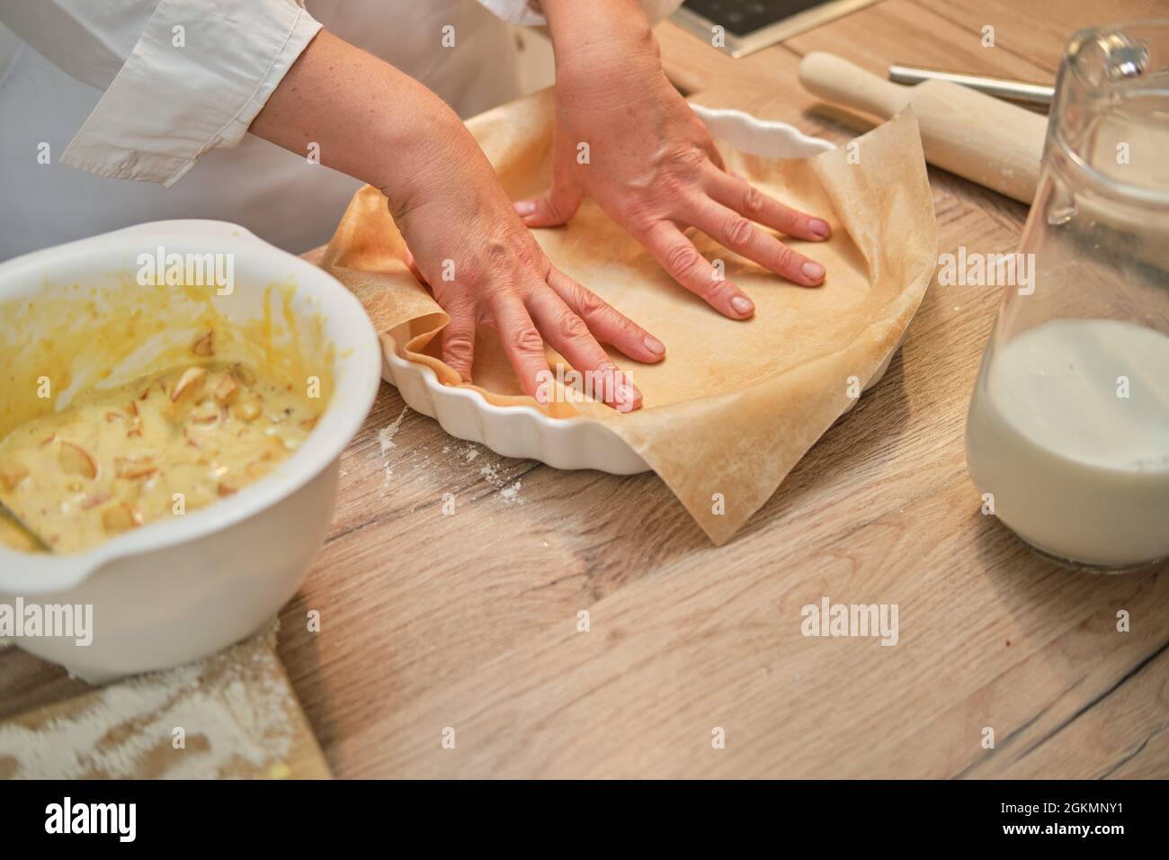 An adult woman in white chef clothes cooking pie in a beige kitchen ...