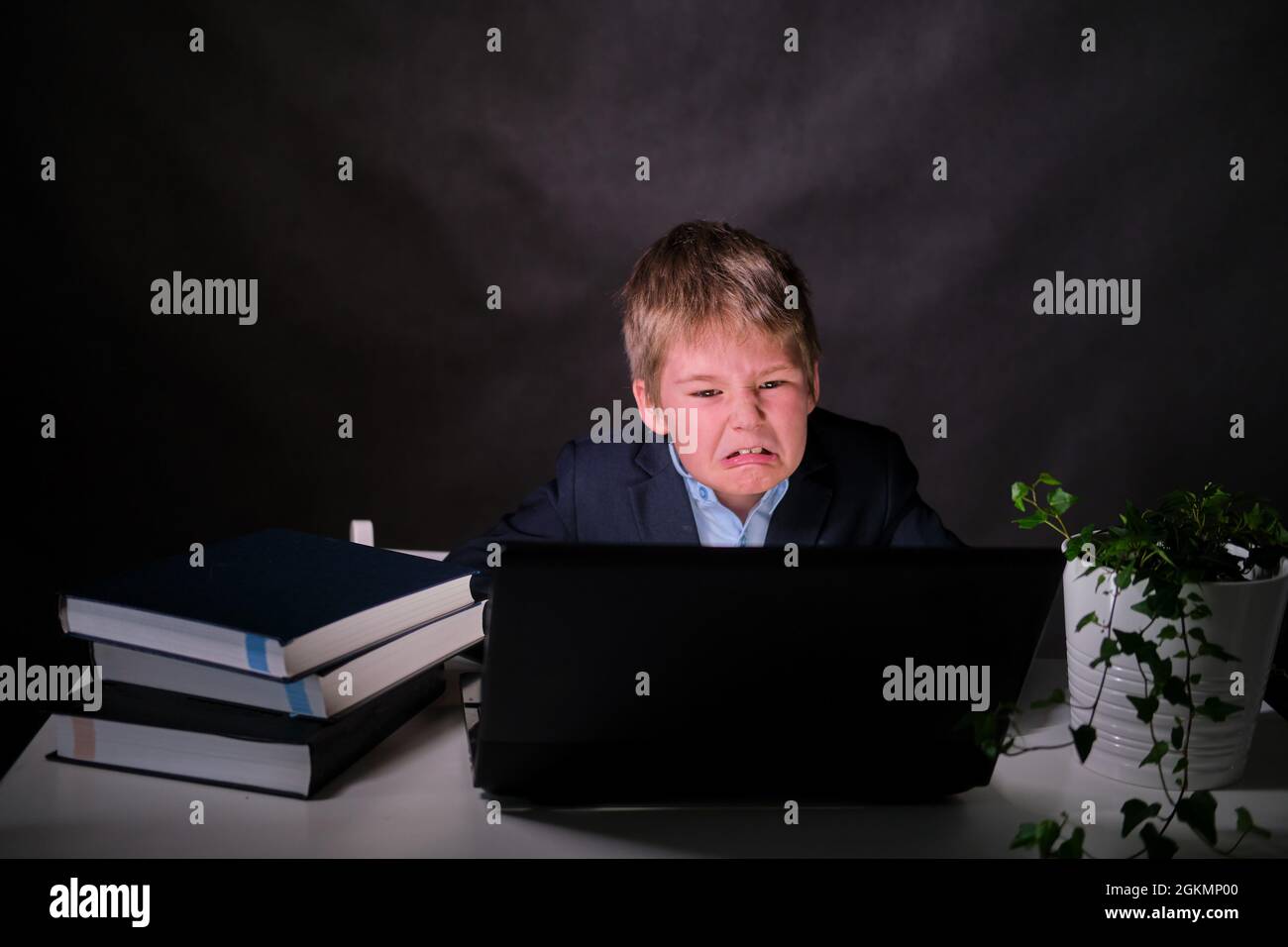 A sad boy in a school suit is crying at the computer, copy space on a ...