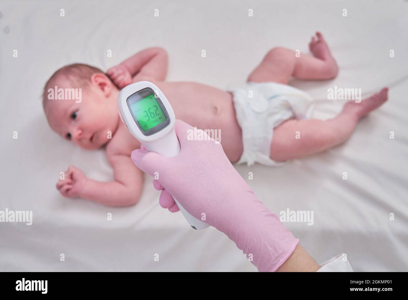 Doctor checks the temperature of the newborn baby with a thermometer. A ...