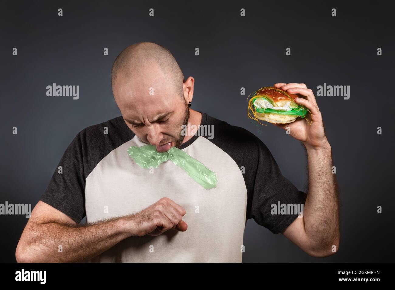 The concept of fast food and ecology. A bald man with a beard, spitting ...
