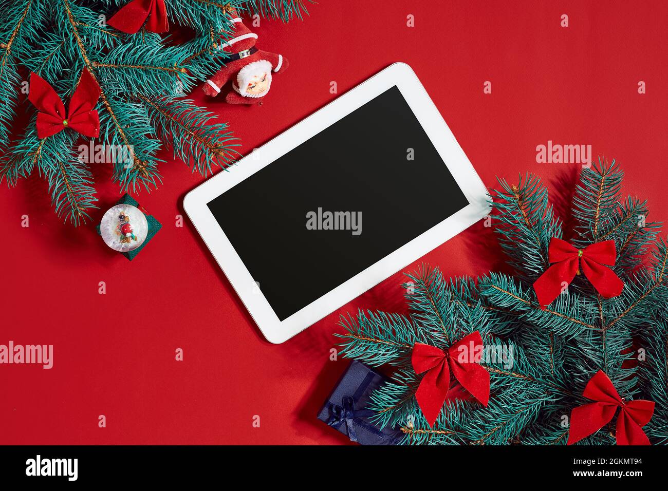 Christmas decorations and white tablet with black screen on hot red ...