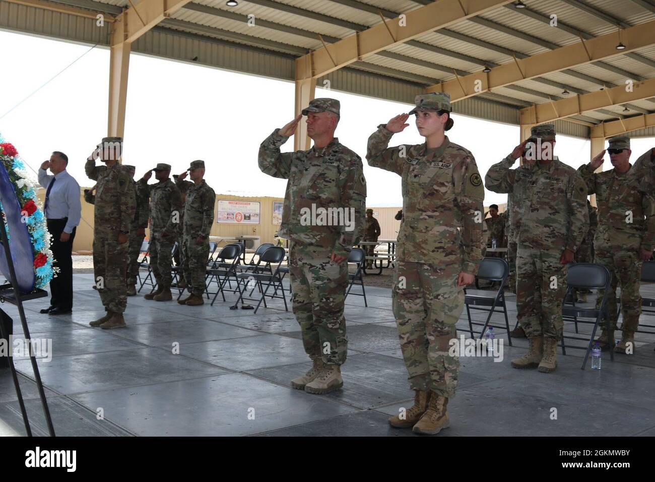 Attendees salute during a Memorial Day ceremony at Camp Buehring ...