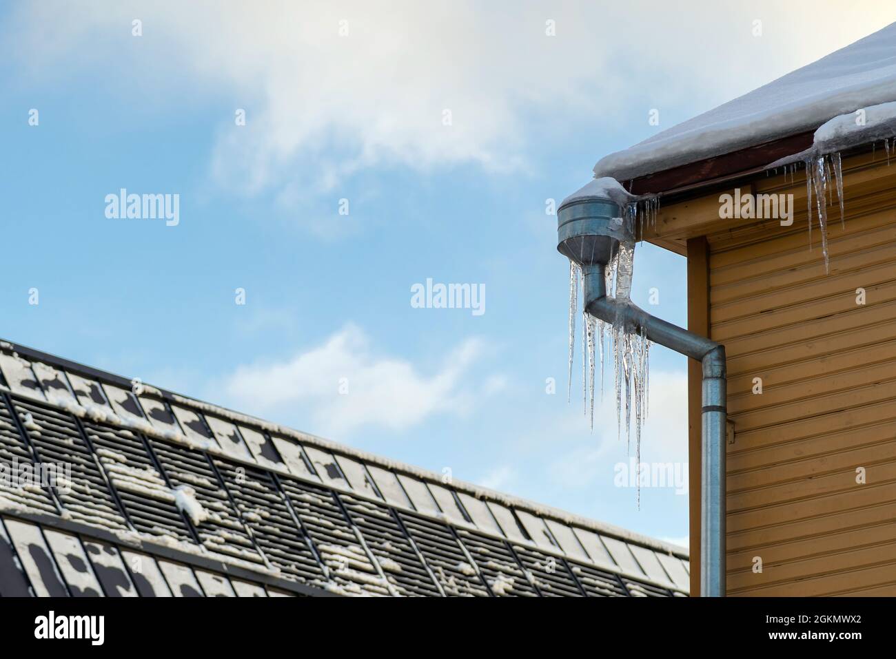 Sharp icicles hanging on the edge of the roof. Melting snow forms ...