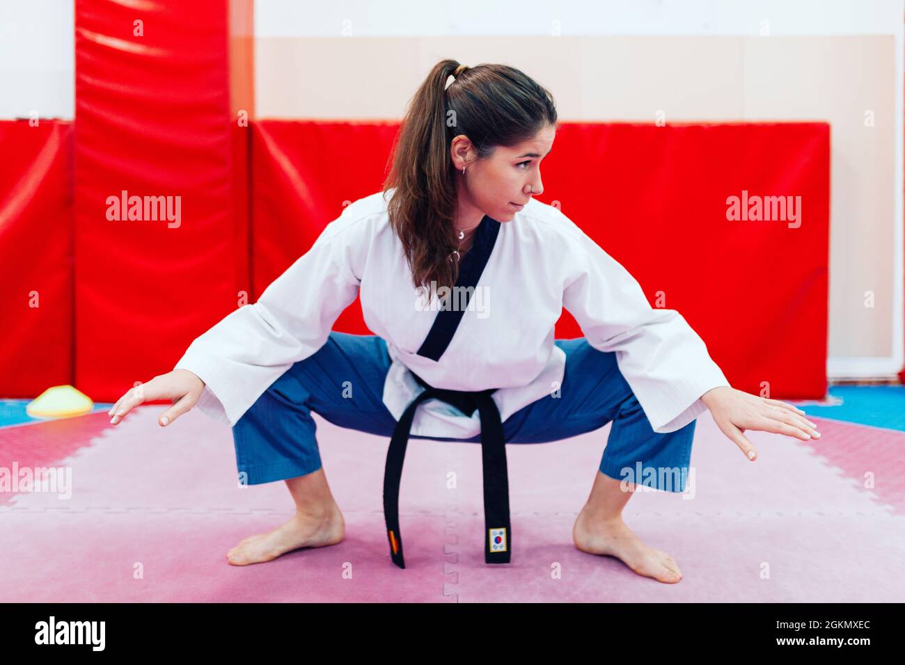 Young woman stretching in a dojo wearing taekwondo dobok Stock Photo ...