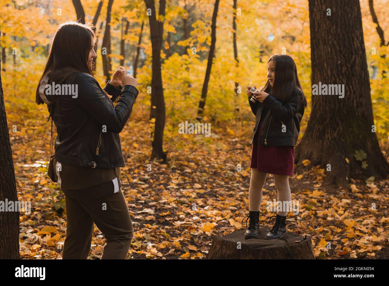 Child girl photographer takes pictures of a mother in the park in ...