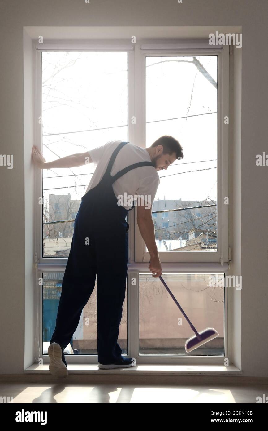 Young man washing window in office Stock Photo - Alamy