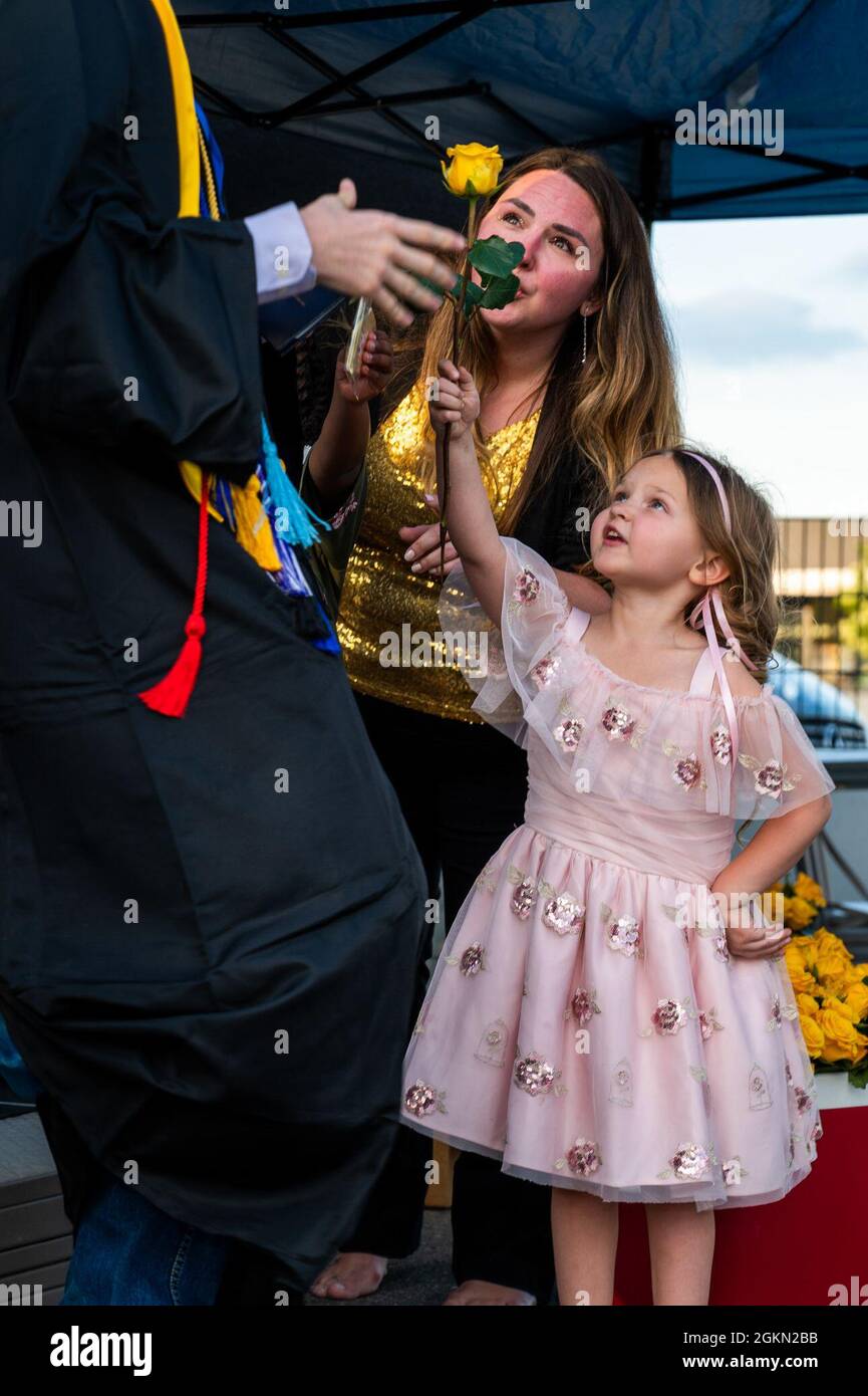 A girl gives a Stuttgart High School graduate a yellow rose as he walks ...