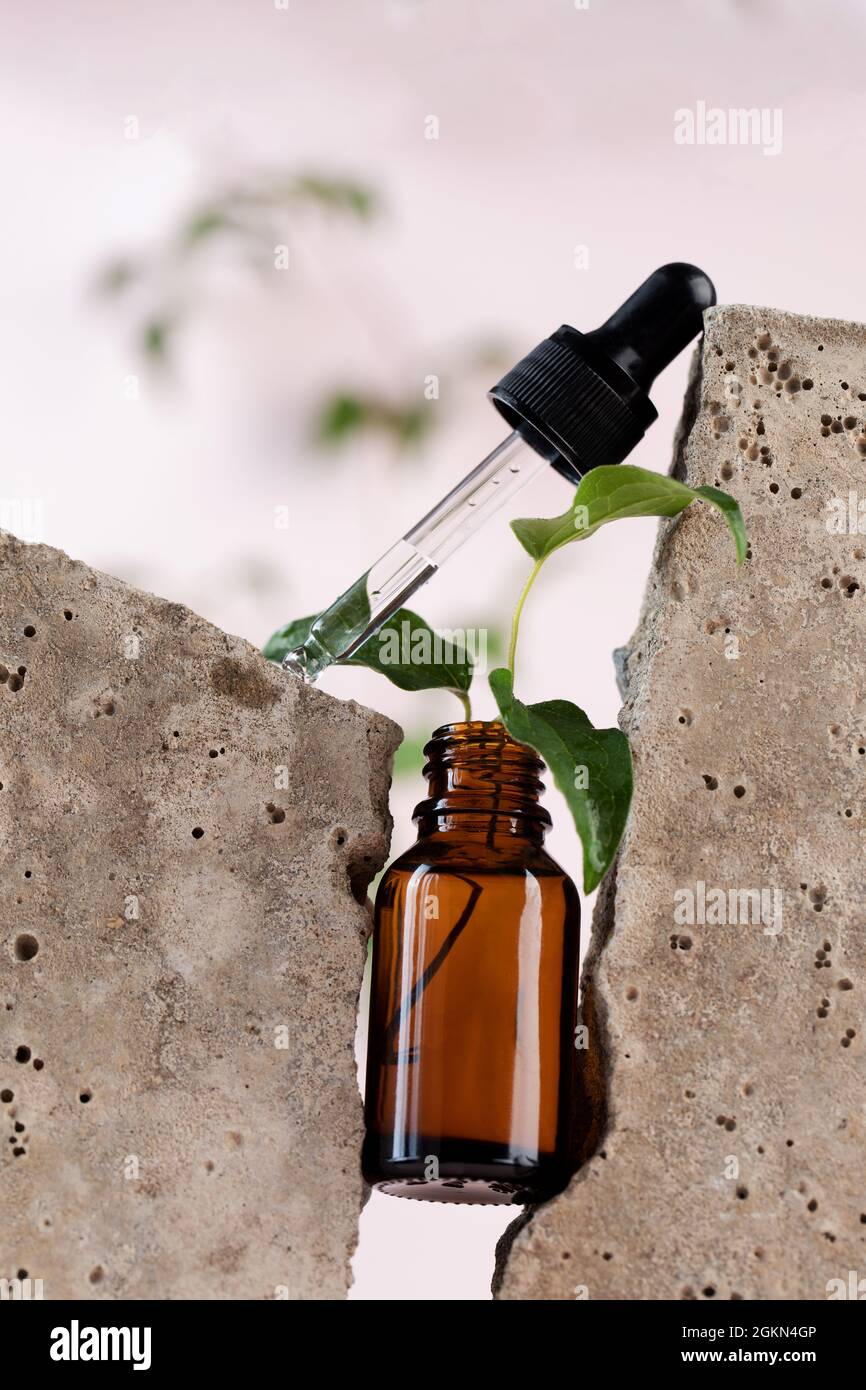 Bottle of natural essential oil with pipette between weathered concrete ...