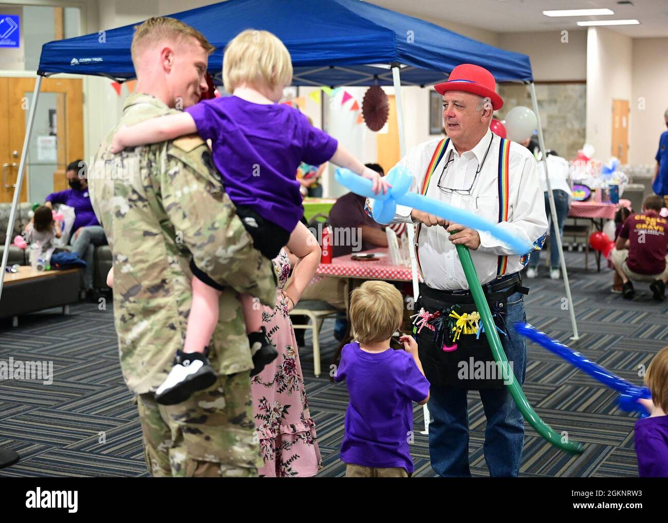 An Airman and his family watch as a balloon artist creates an animal ...