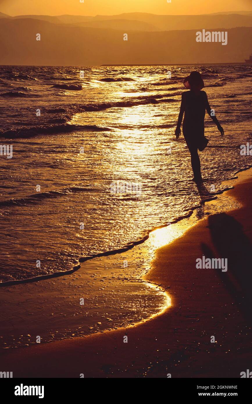 A Woman Walks On A Beach At Sunset Silhouette Photography Golden Hour
