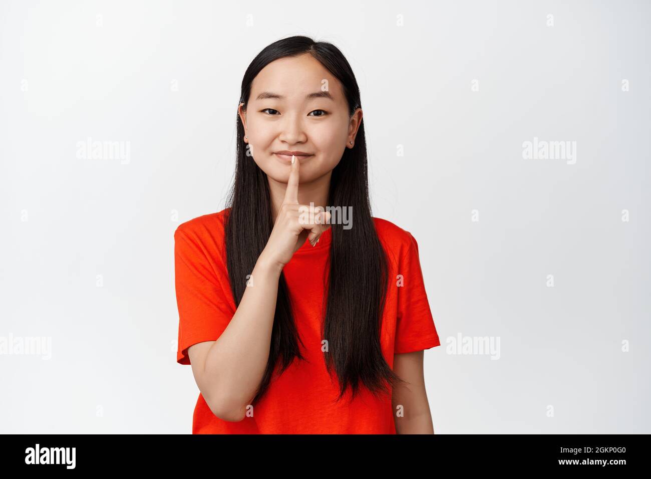 Cute asian girl smiling and shushing, showing shhh hush sign, telling ...