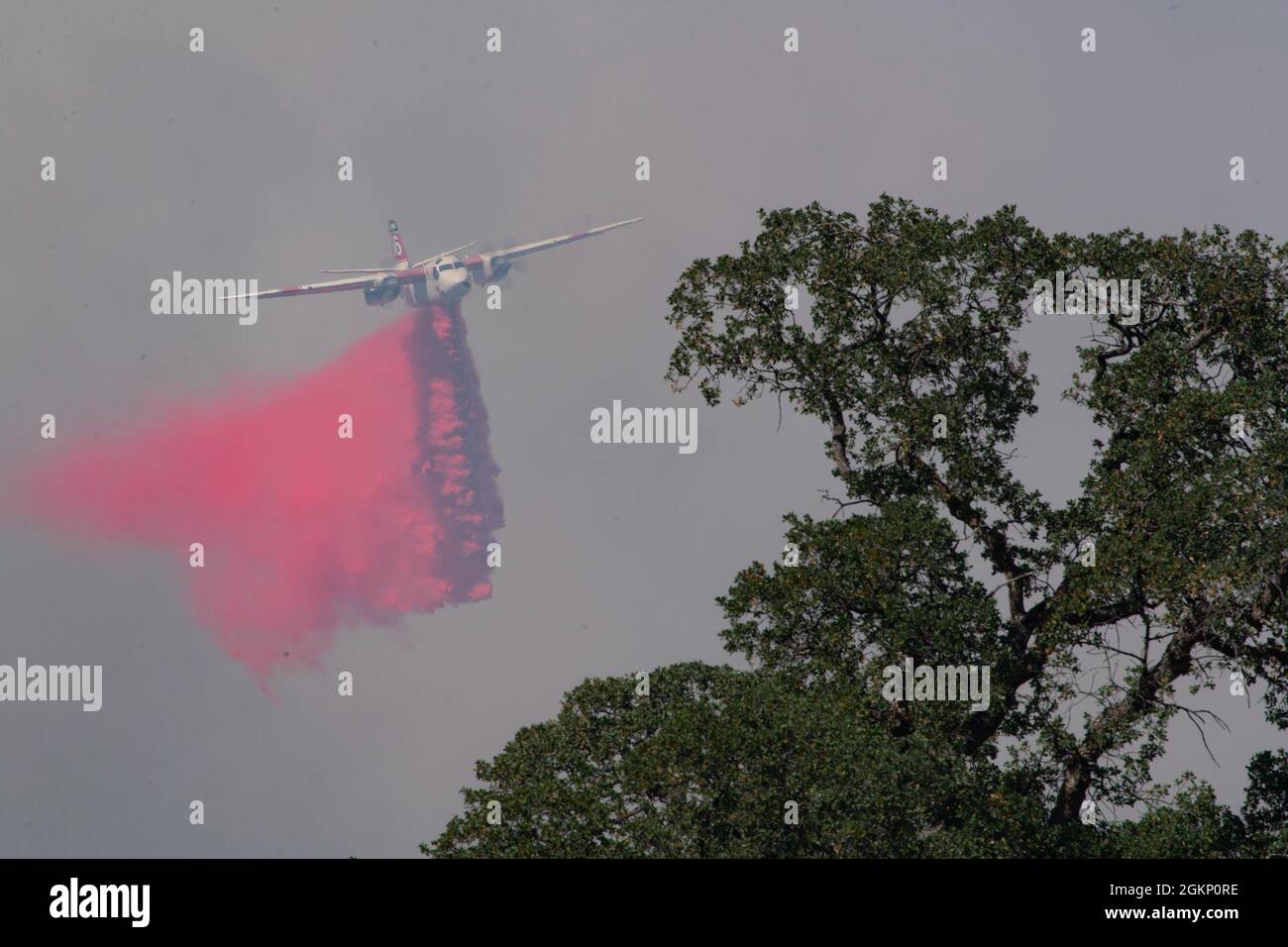 A Cal Fire S-2T Airtanker conducts an aerial fire retardant drop to ...