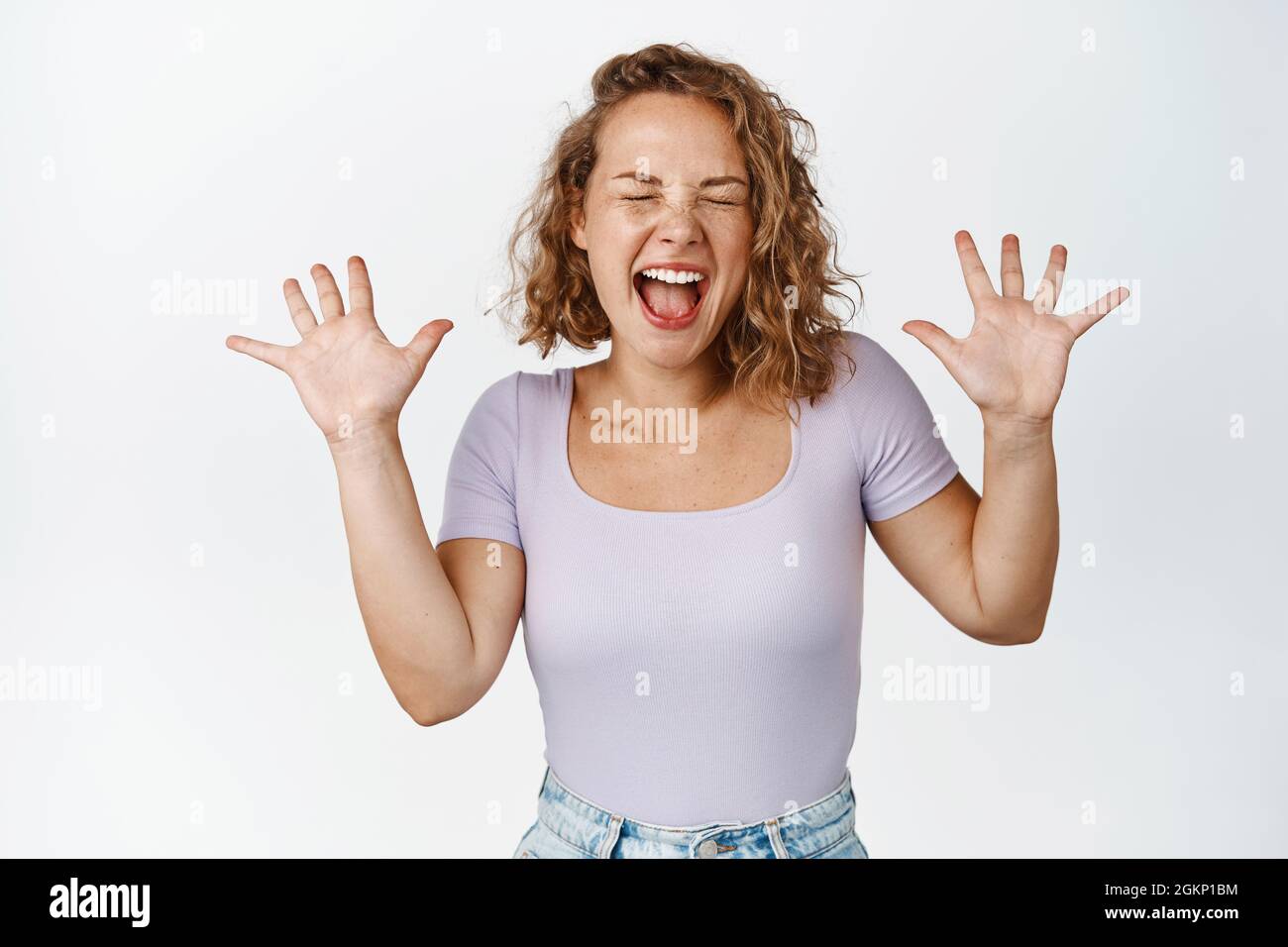 Excited blond girl screaming and shaking raised hands, shouting with ...