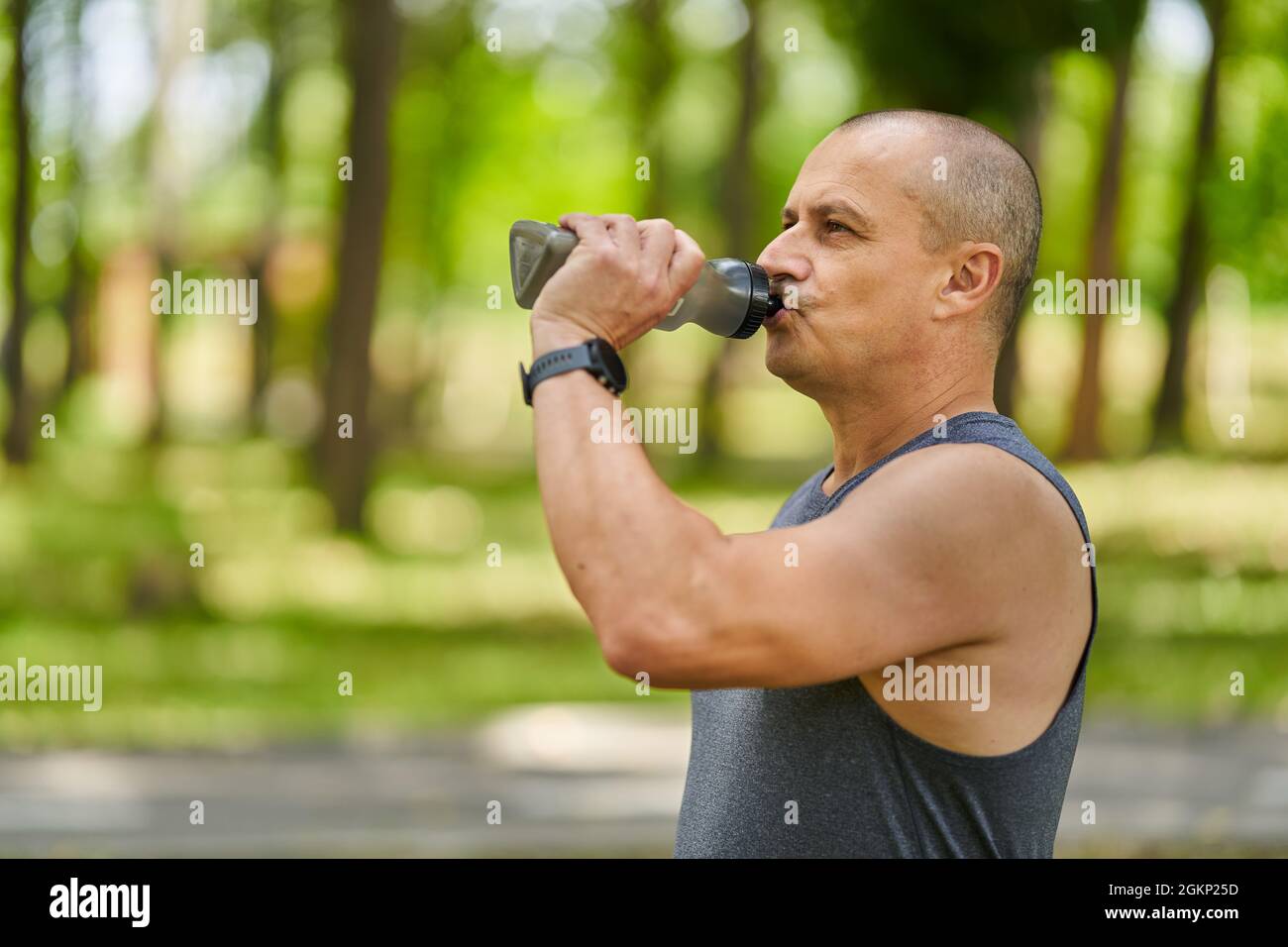 Runner drinking water after working out in the park Stock Photo - Alamy