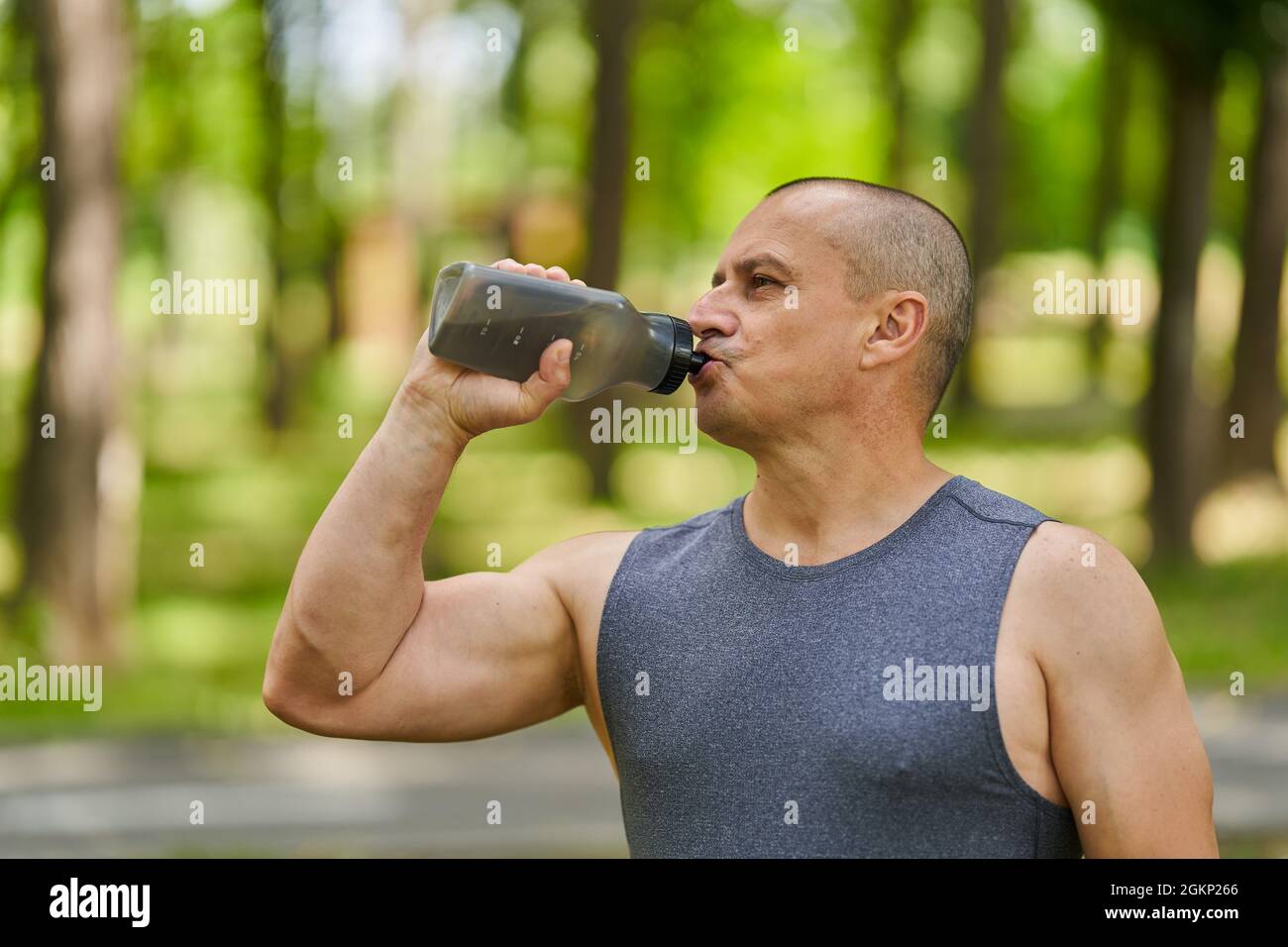 Runner drinking water after working out in the park Stock Photo - Alamy