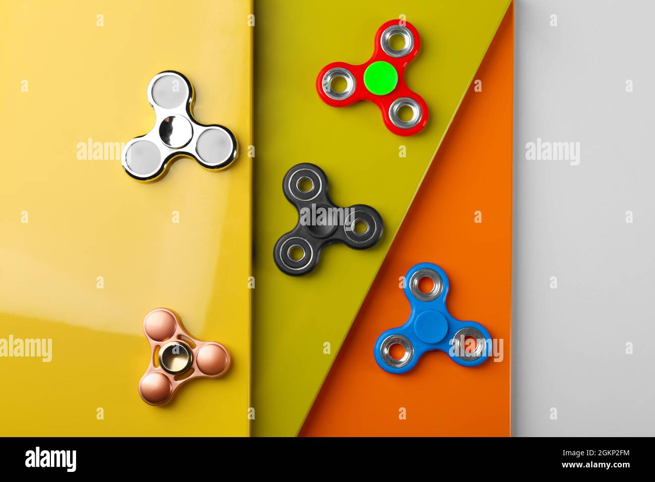 Different modern spinners on colorful background, top view Stock Photo ...