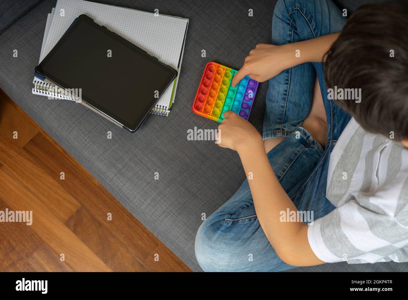 Boy playing with sensory pop it fidget toy while doing homework at home ...