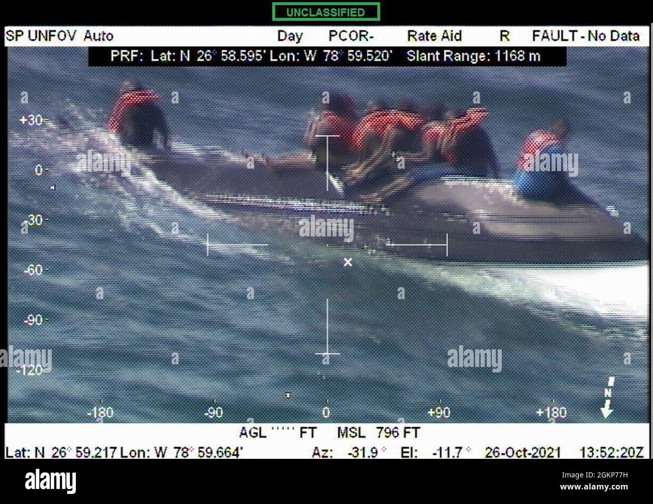 Seven people sit upon the hull of a capsized boat before being rescued ...