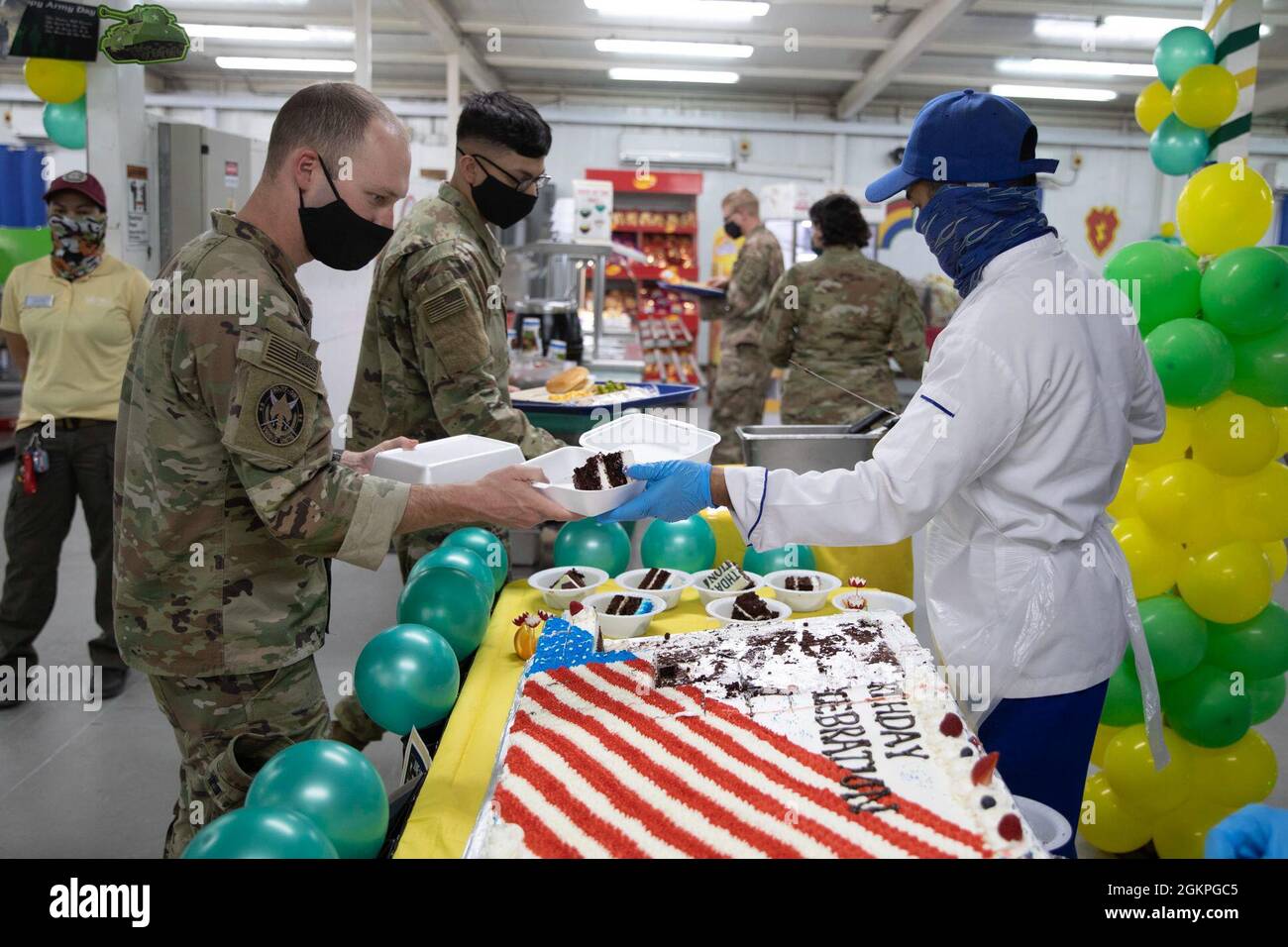 A dining facility worker hands out cake to Soldiers in celebration of ...