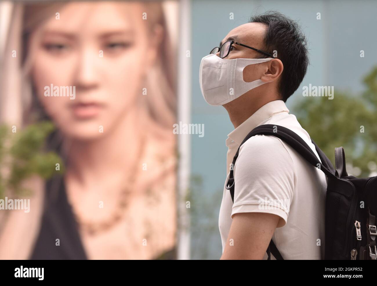 A pedestrian wearing a mask walks by a huge commercial poster on ...
