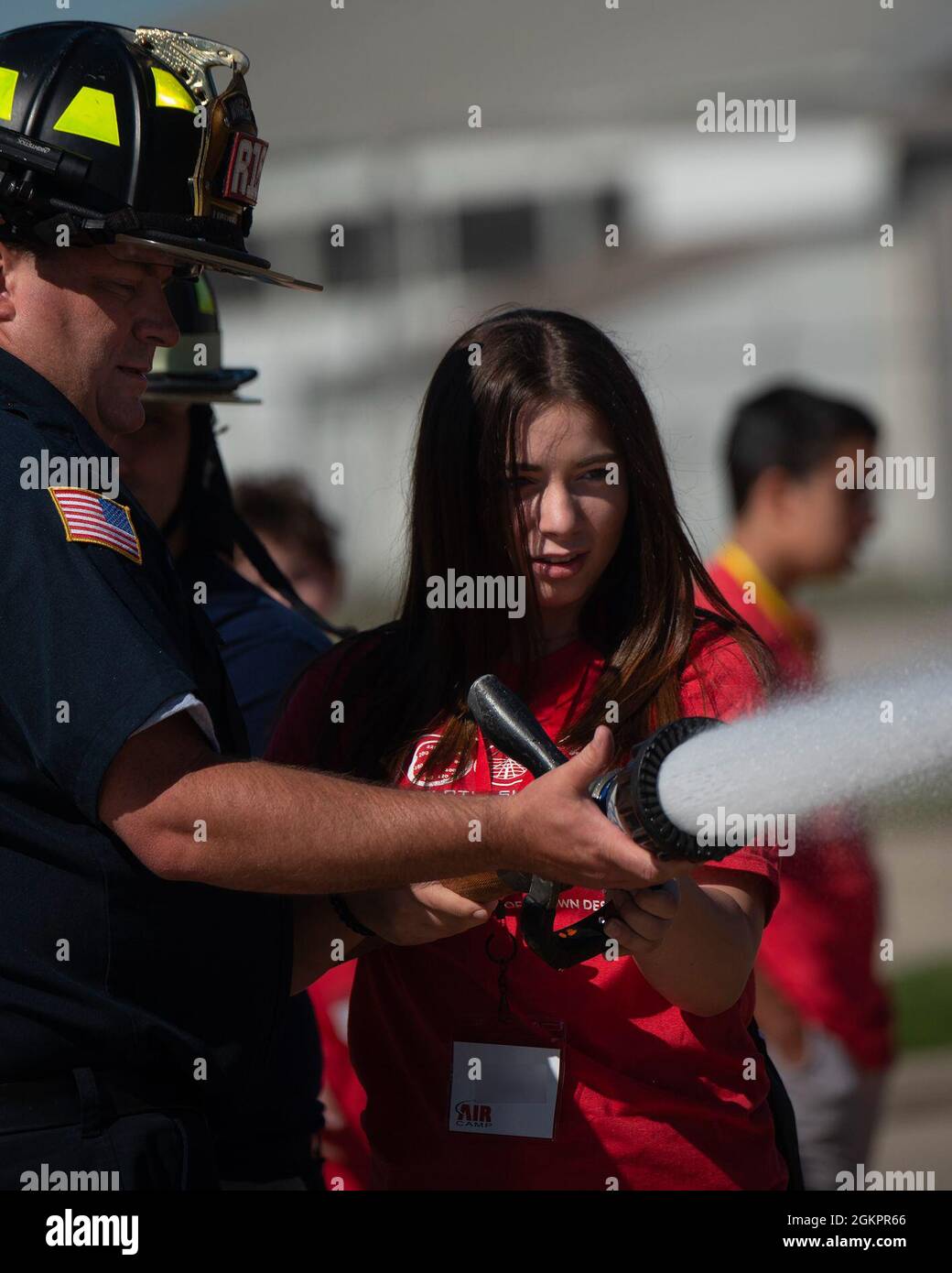 A camper handles a fire hose with the help of firefighter Thomas Trost ...