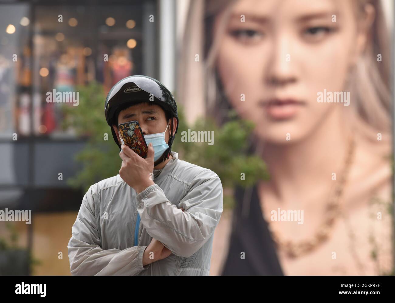 A pedestrian wearing a mask walks by a huge commercial poster on ...