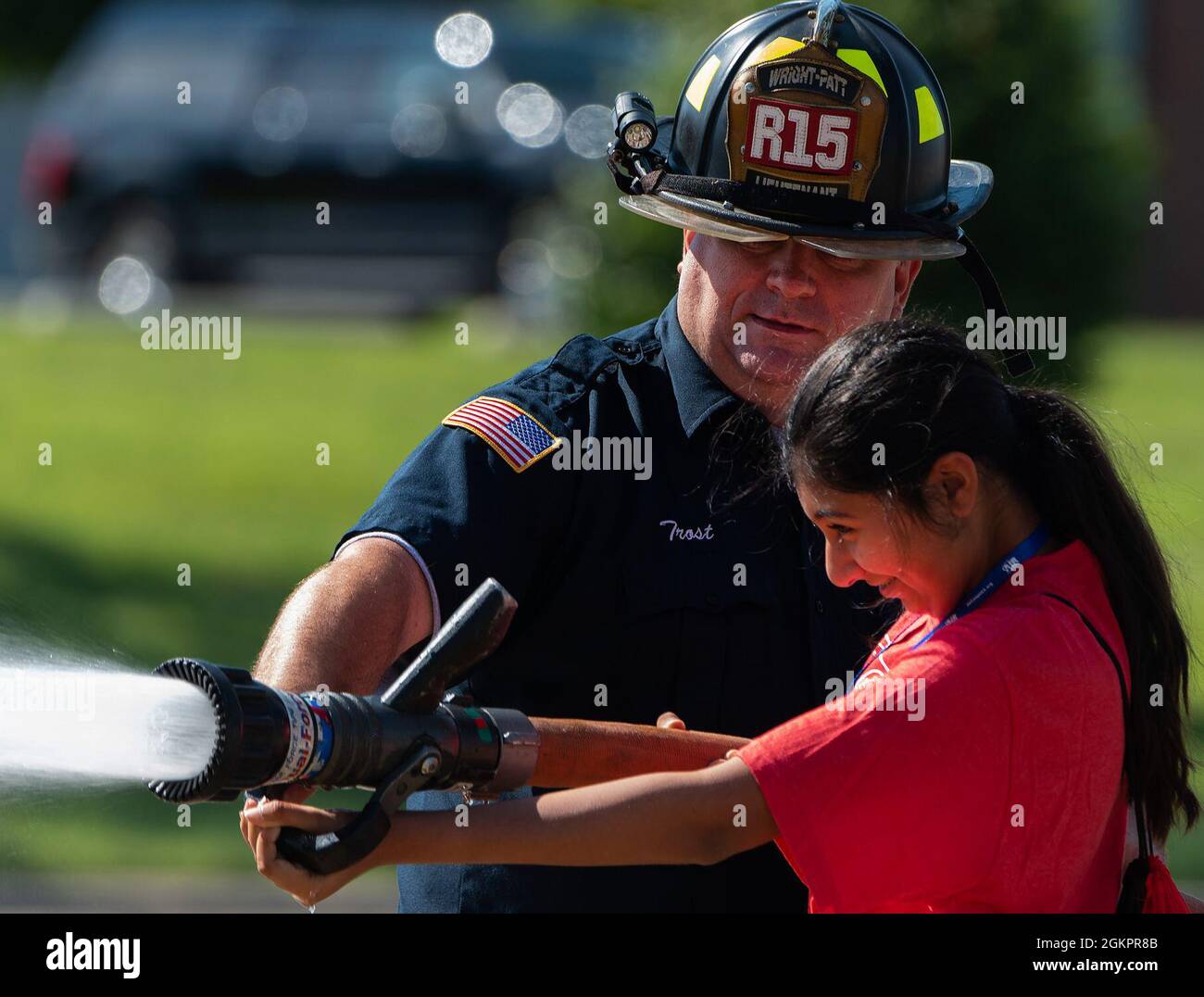 A camper handles a fire hose with the help of firefighter Thomas Trost ...