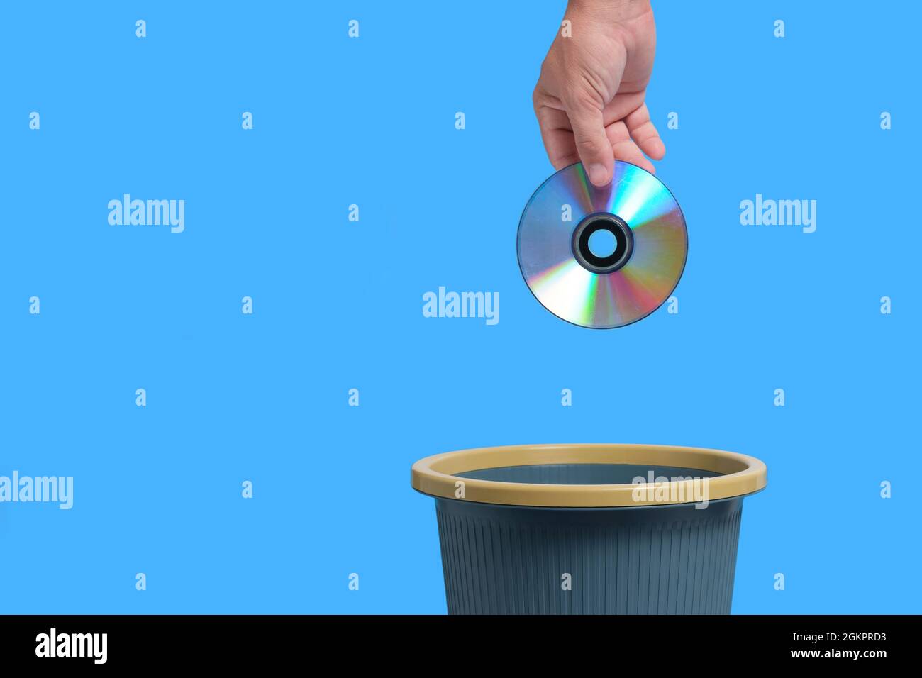 Old scratched CD is thrown into the trash on a blue background.Outdated ...