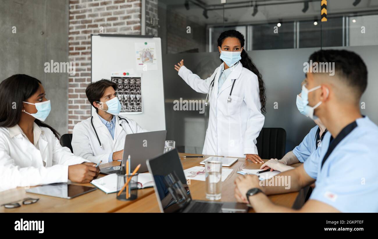 Multiracial group of doctors in face masks having medical conference ...