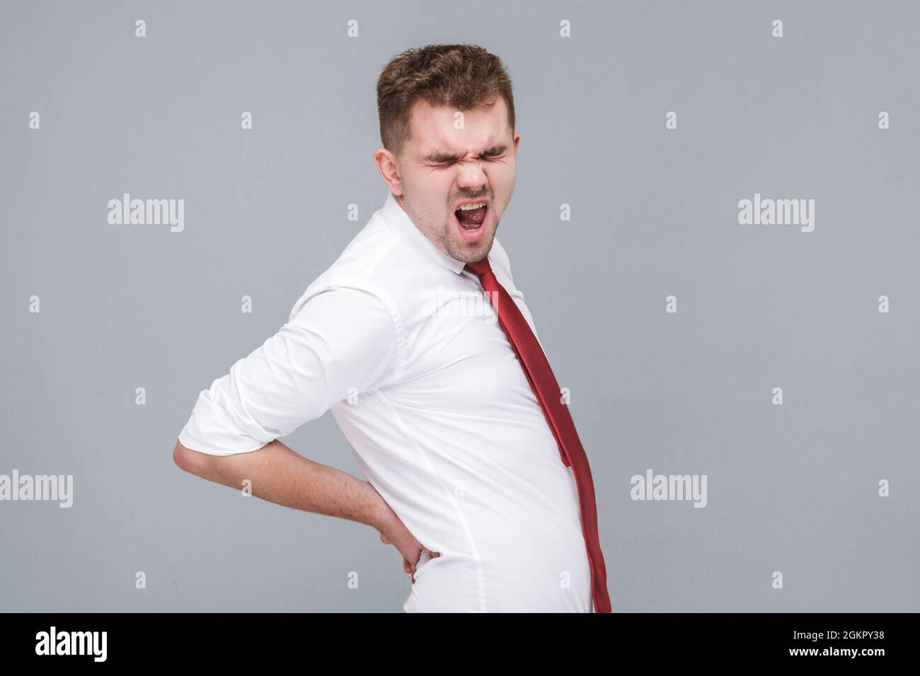 Backache or spine or kidney pain. Portrait of young sick man in white ...
