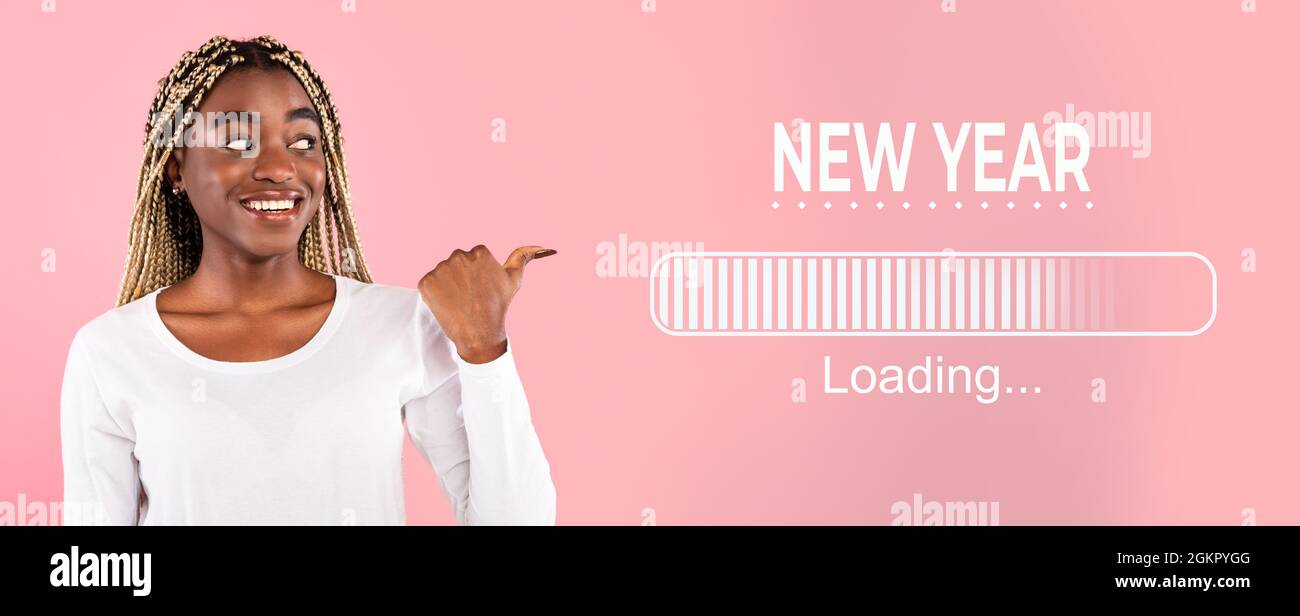 Happy black woman with Afro braids pointing aside at New Year loading ...