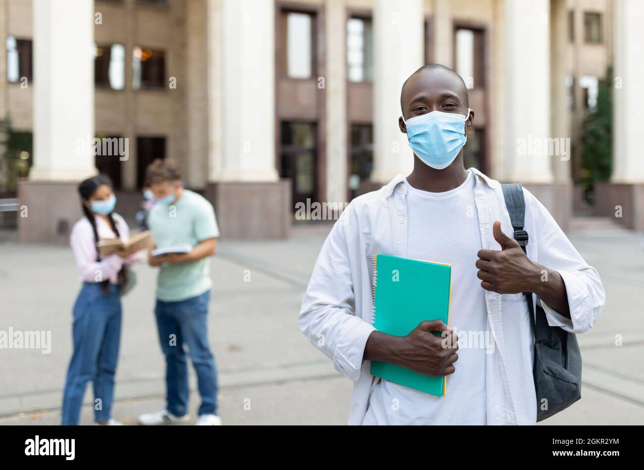Study during coronavirus. Black male student wearing face mask, holding ...