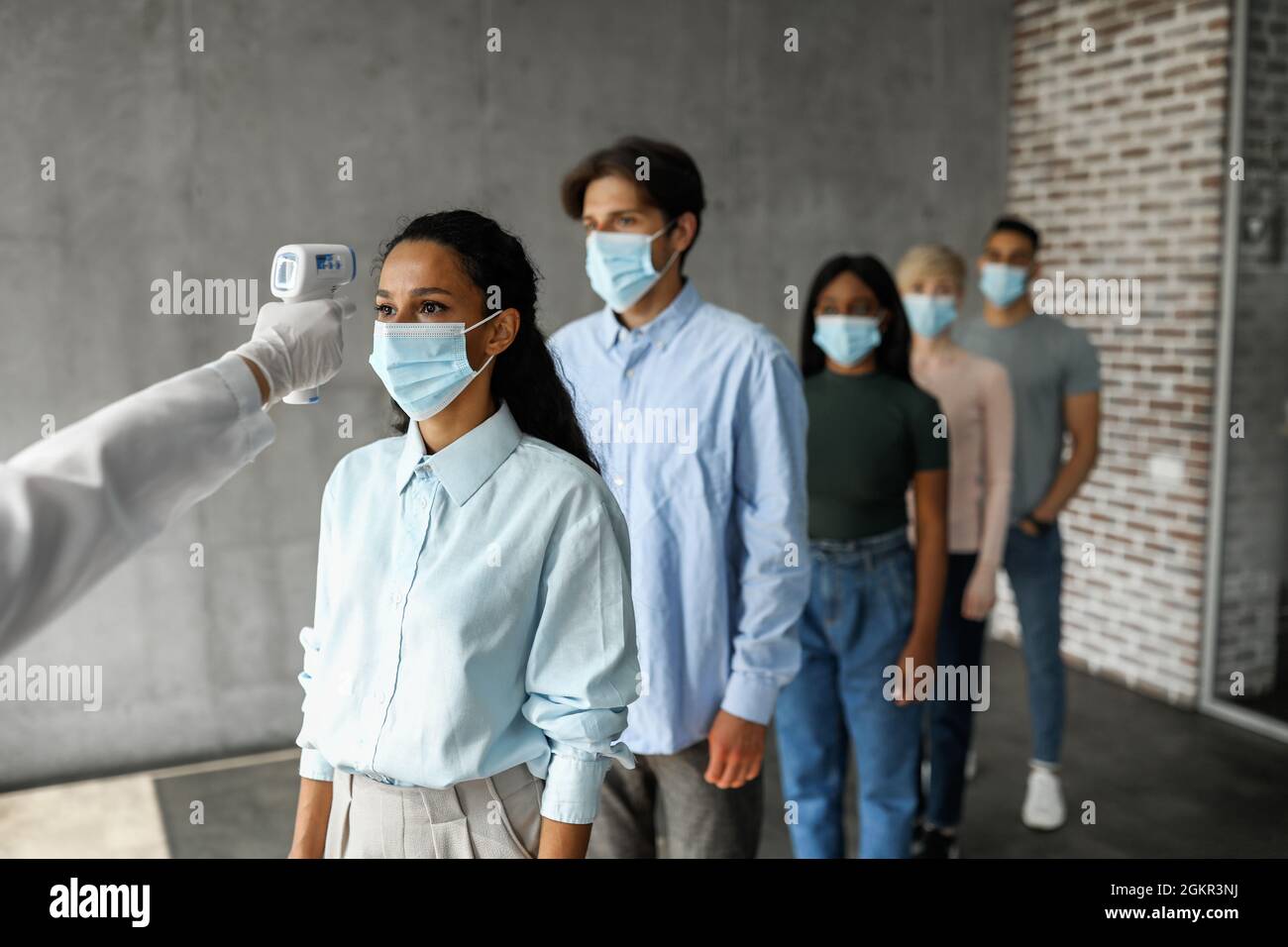 International group of people in face masks checking body temperature ...