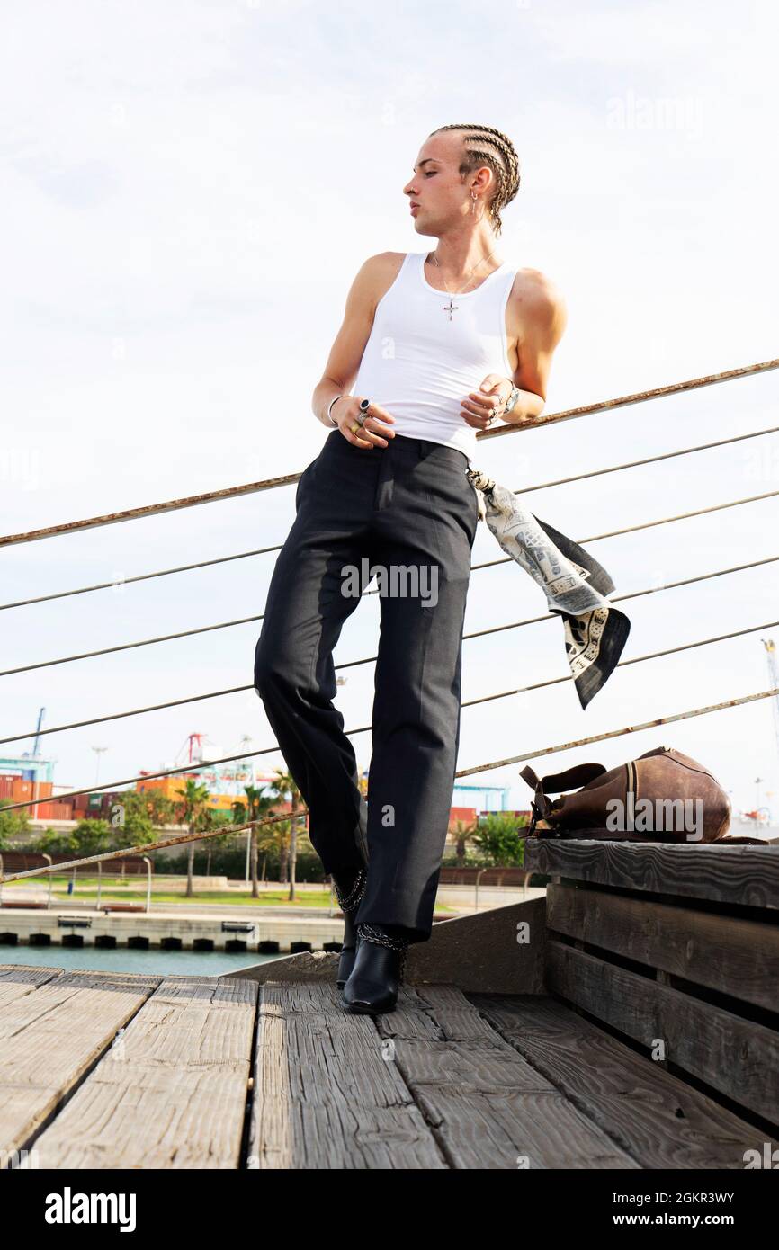 Vertical shot of a handsome Spanish male model in a tank top leaning on ...