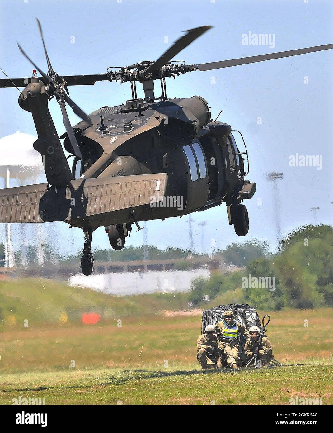 A UH-60 Black Hawk helicopter descends toward an instructor, ammunition ...