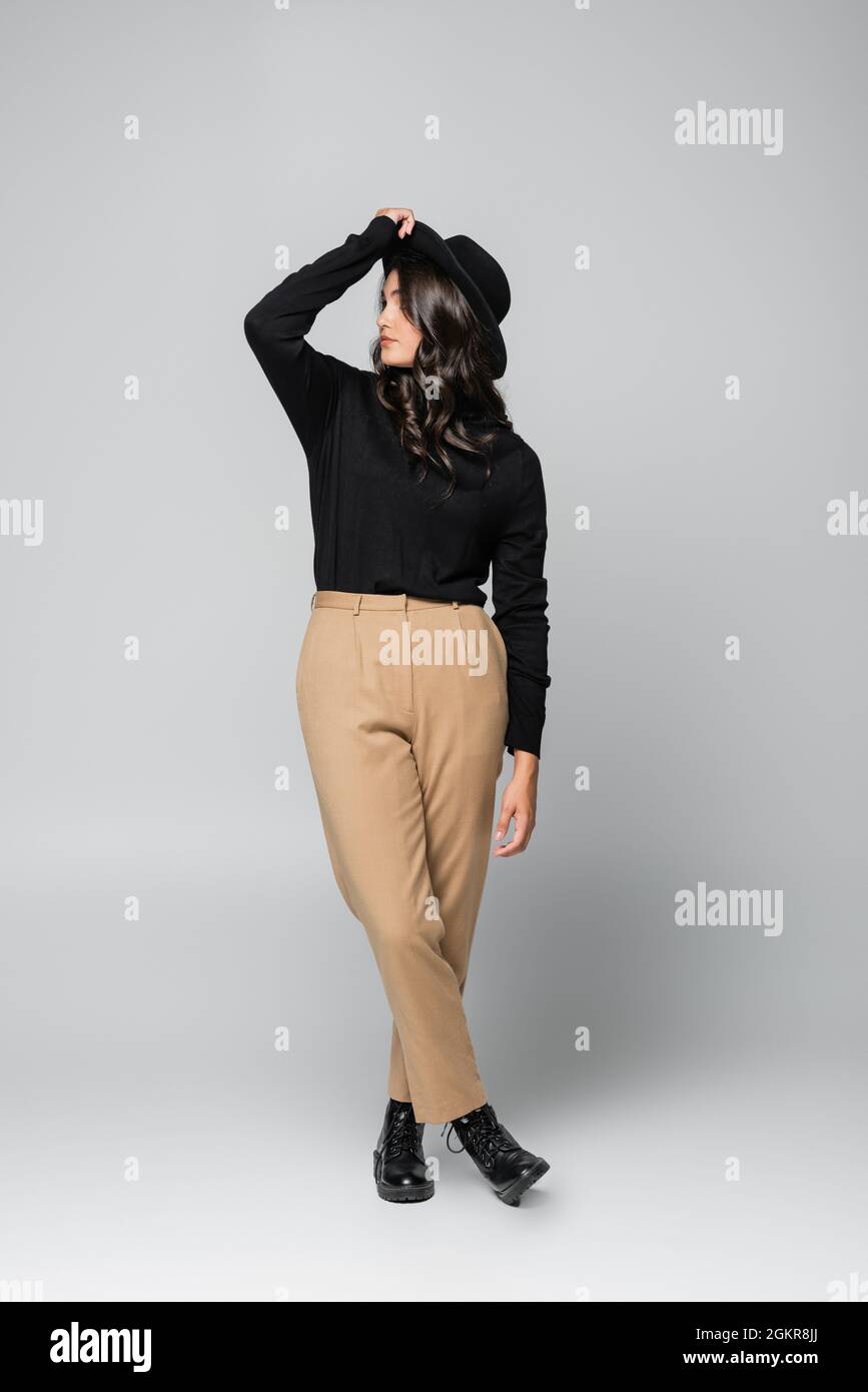 full length of young model in fedora hat and stylish outfit posing on ...