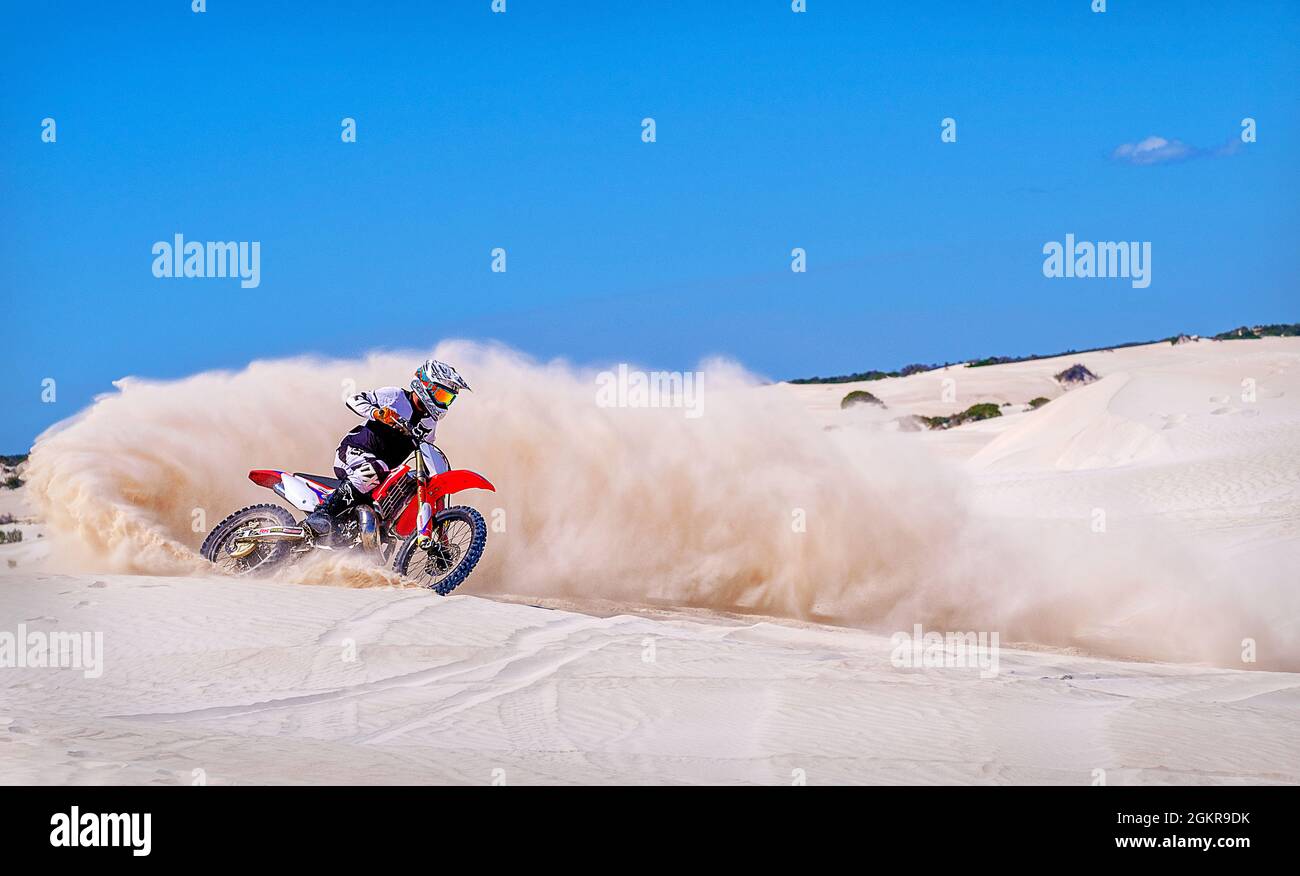 Trial bike rider kicking up sand at the sand dunes of Lancelin, Western ...