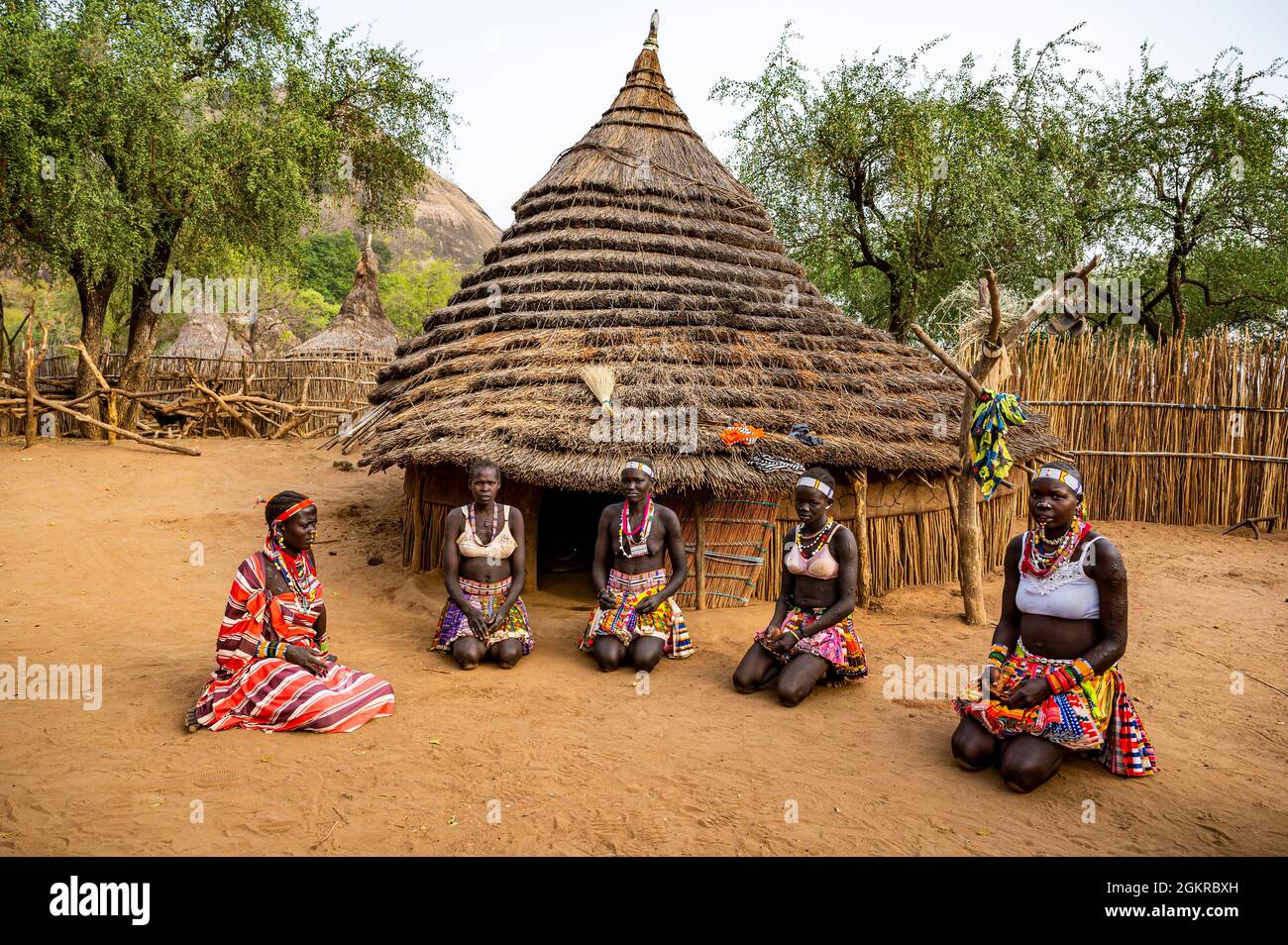 Young women in front of a traditional village hut of the Laarim tribe ...
