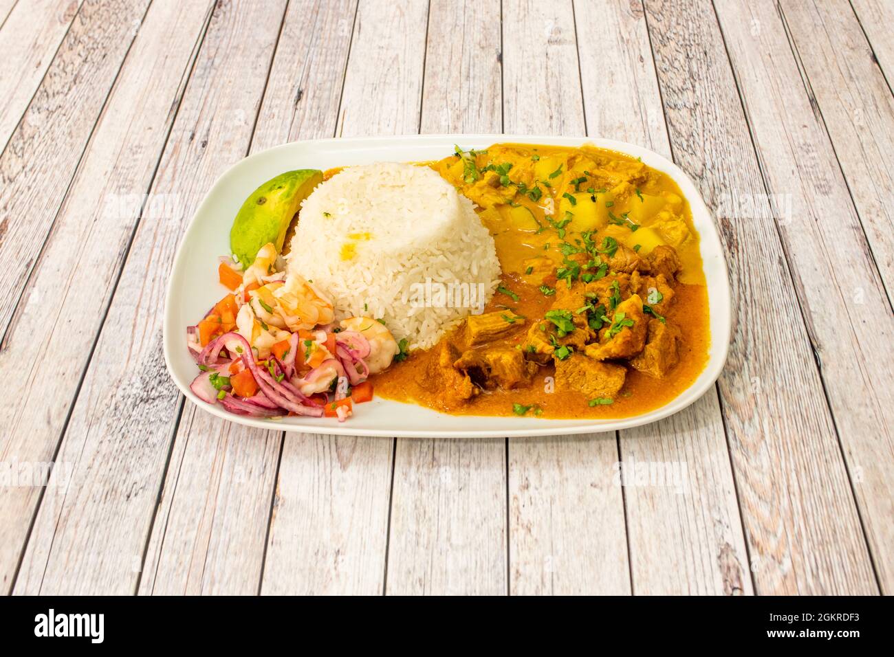 Peruvian stew of pork and chicken with potatoes, avocado wedge, shrimp ...