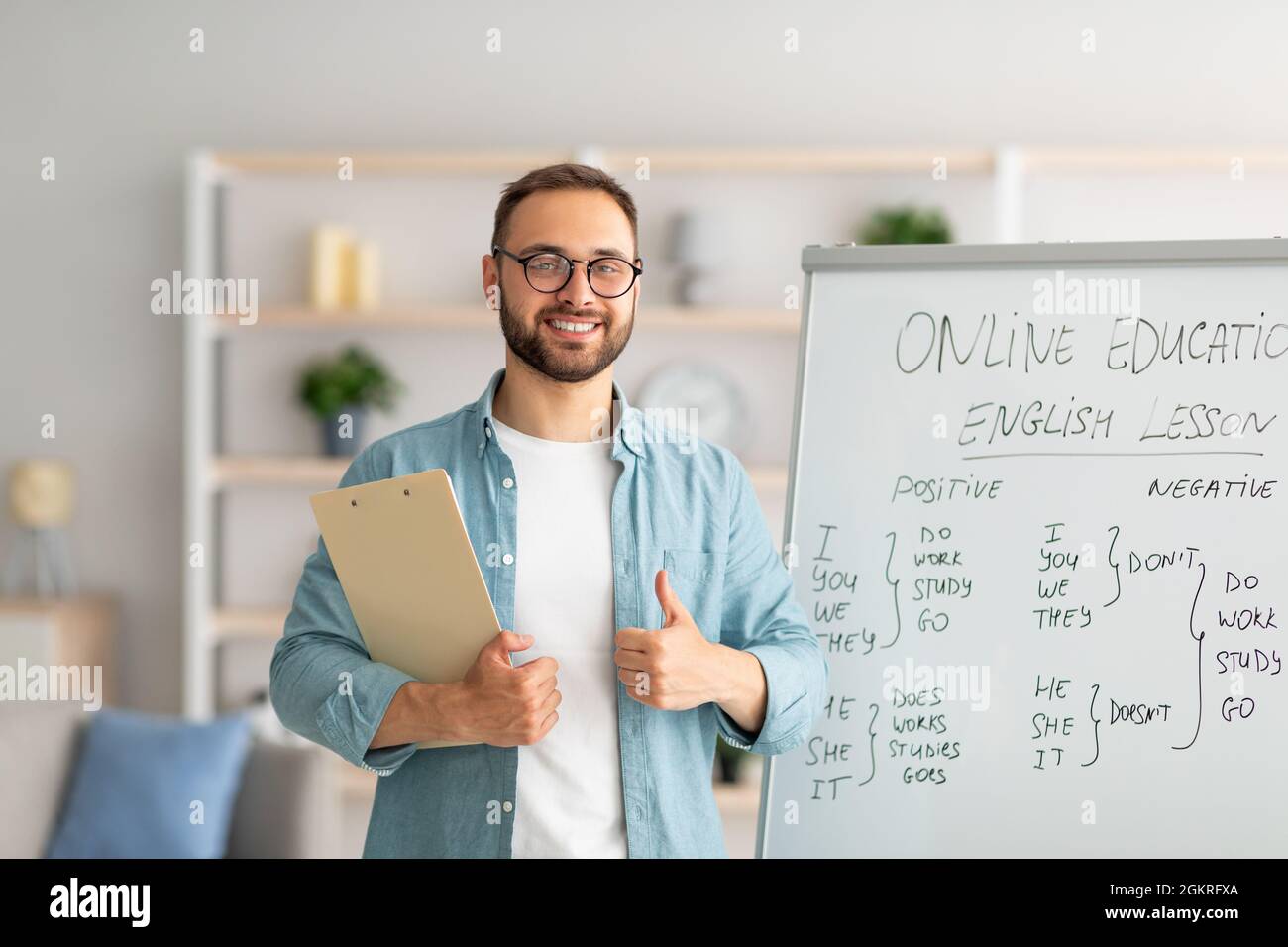 Positive male teacher showing thumb up gesture near blackboard ...
