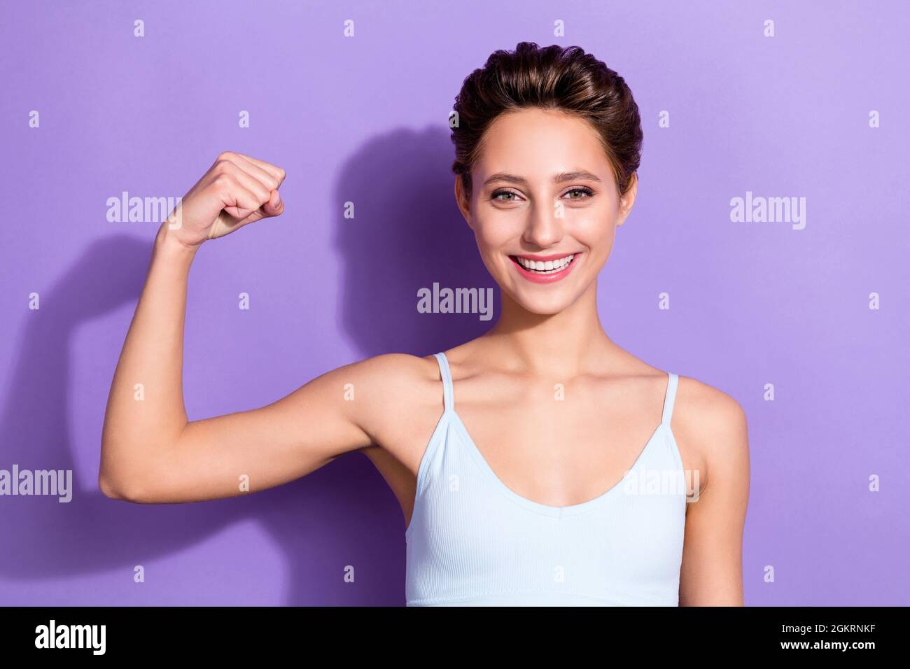 Photo portrait girl in blue top showing strong muscles isolated pastel ...