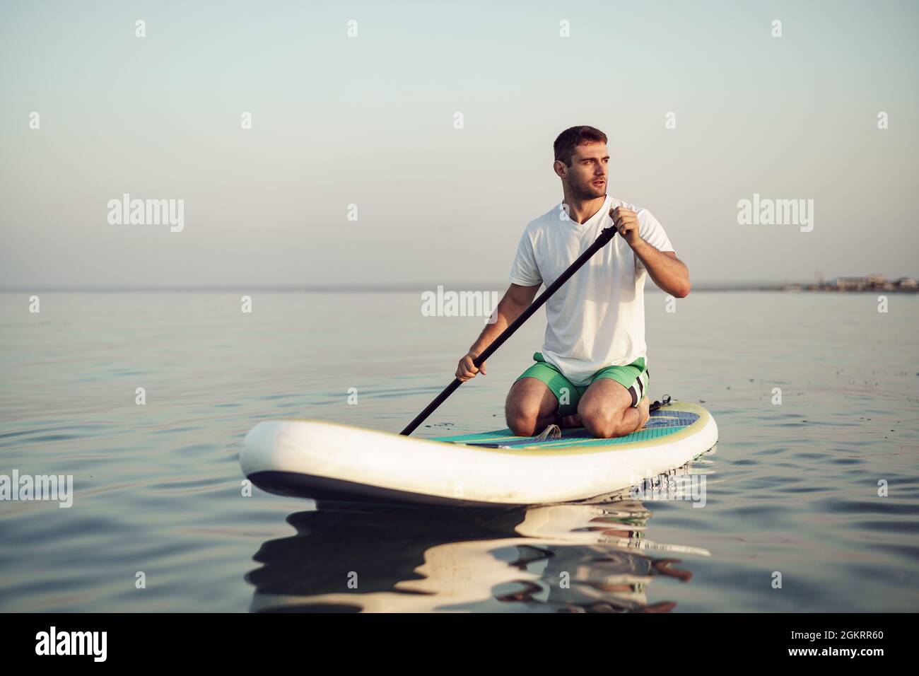 Young man in t-shirt and shorts floating on SUP board Stock Photo - Alamy