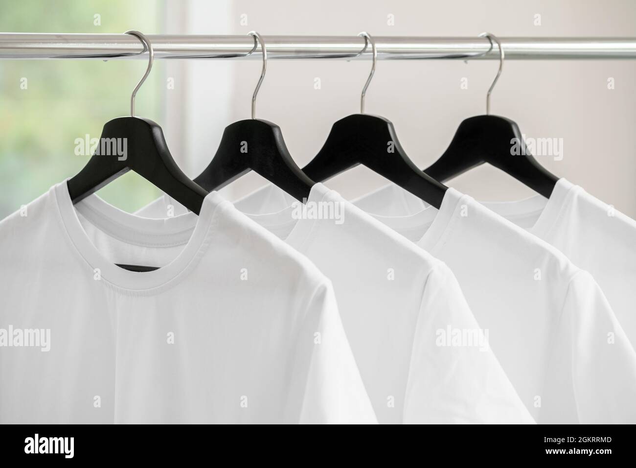 Row of white t-shirts on hangers on rack Stock Photo - Alamy