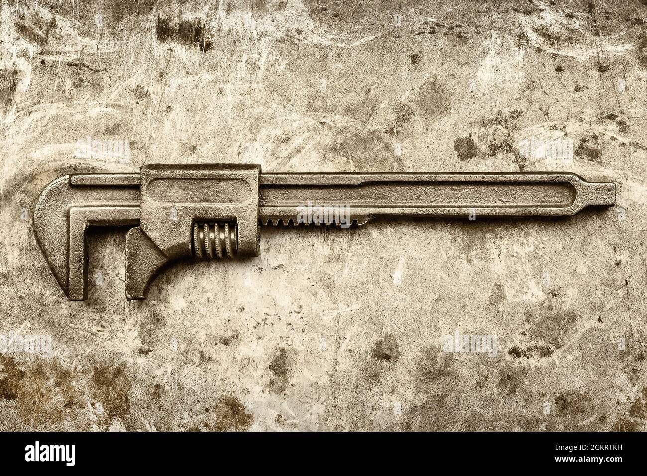 Sepia toned image of a vintage rusty adjustable spanner on an old iron ...