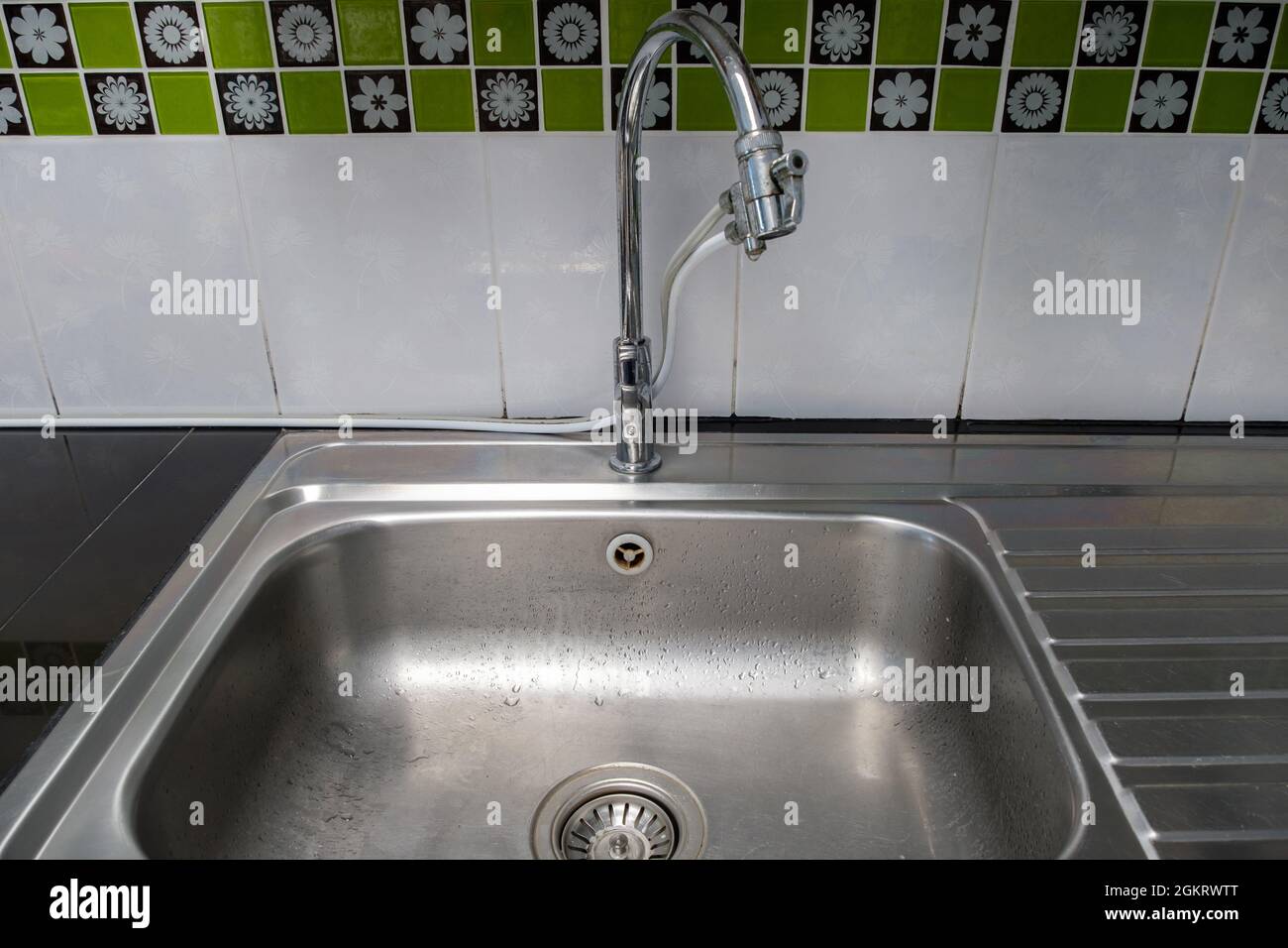 The clean metal sink with the chrome tap after washing on the modern ...