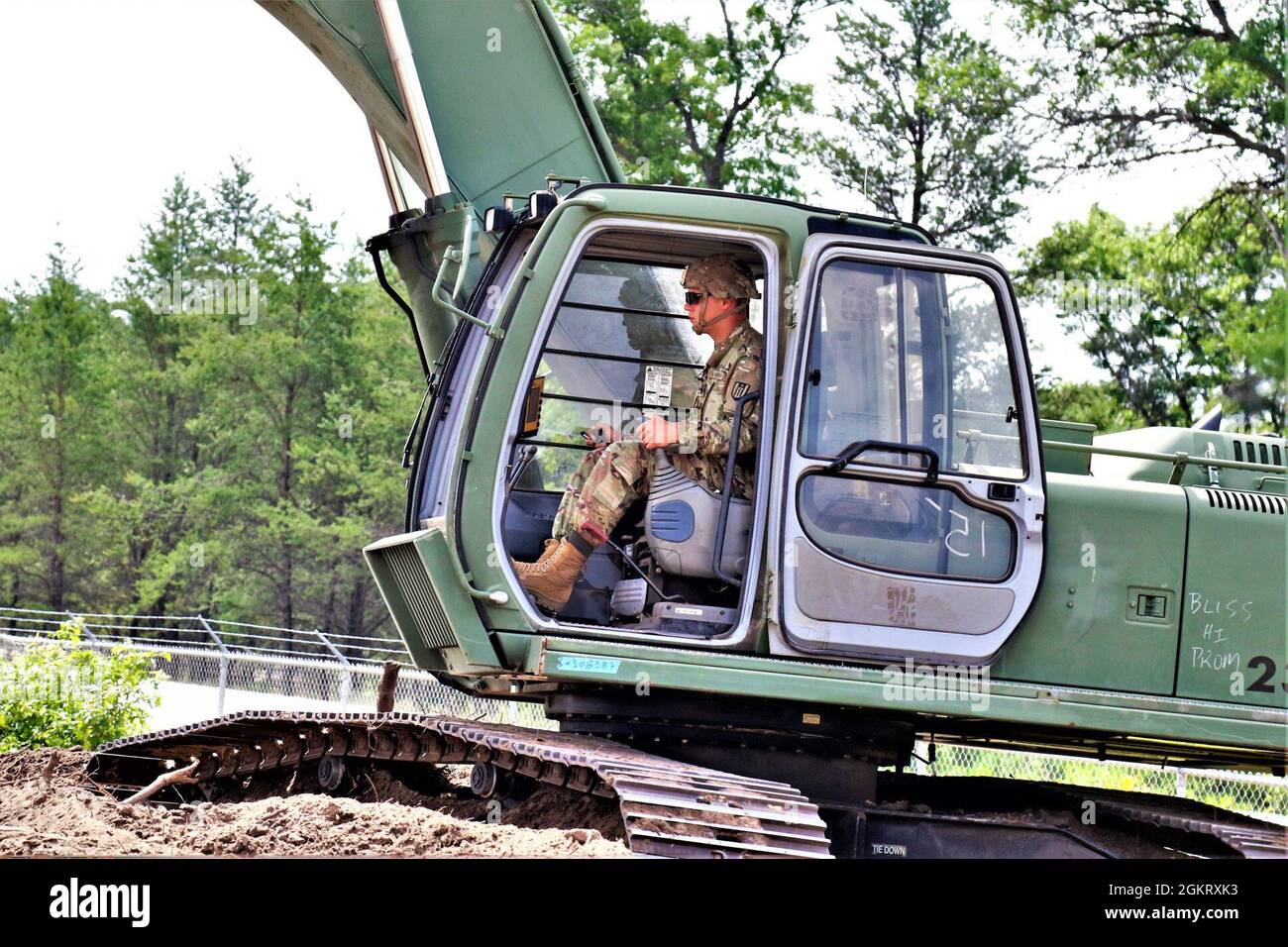 Spc. Ryan Hannegrafs maneuvers an excavator to build a berm at a ...