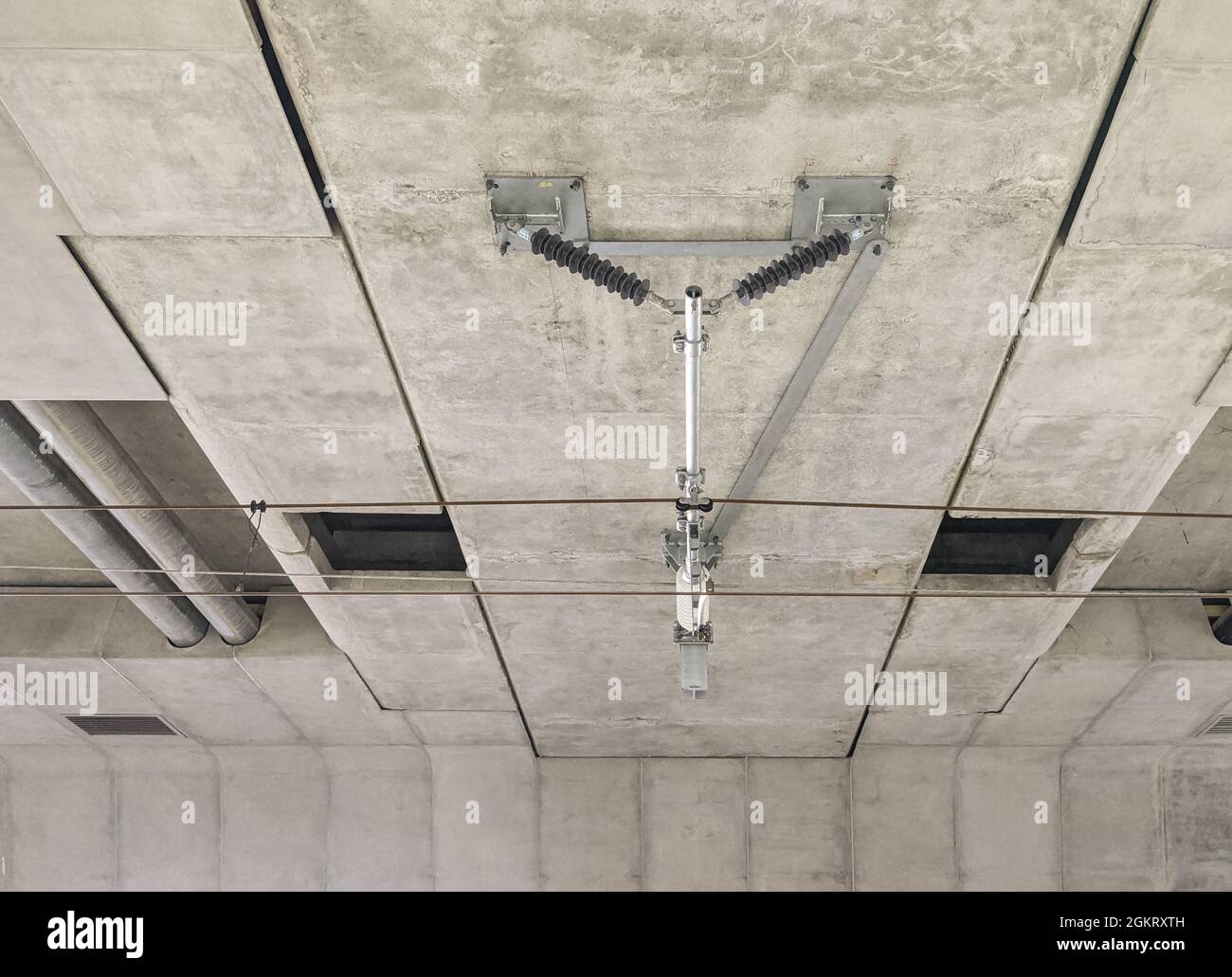 The overhead electric wire is hanging on the concrete ceiling in the ...