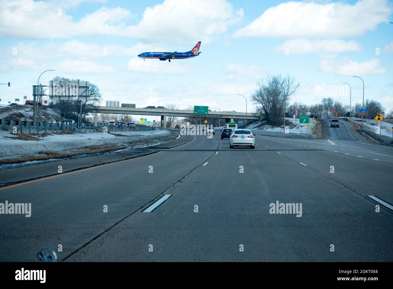Sun Country airplane in flight over Highway 5, approaching the apron of ...