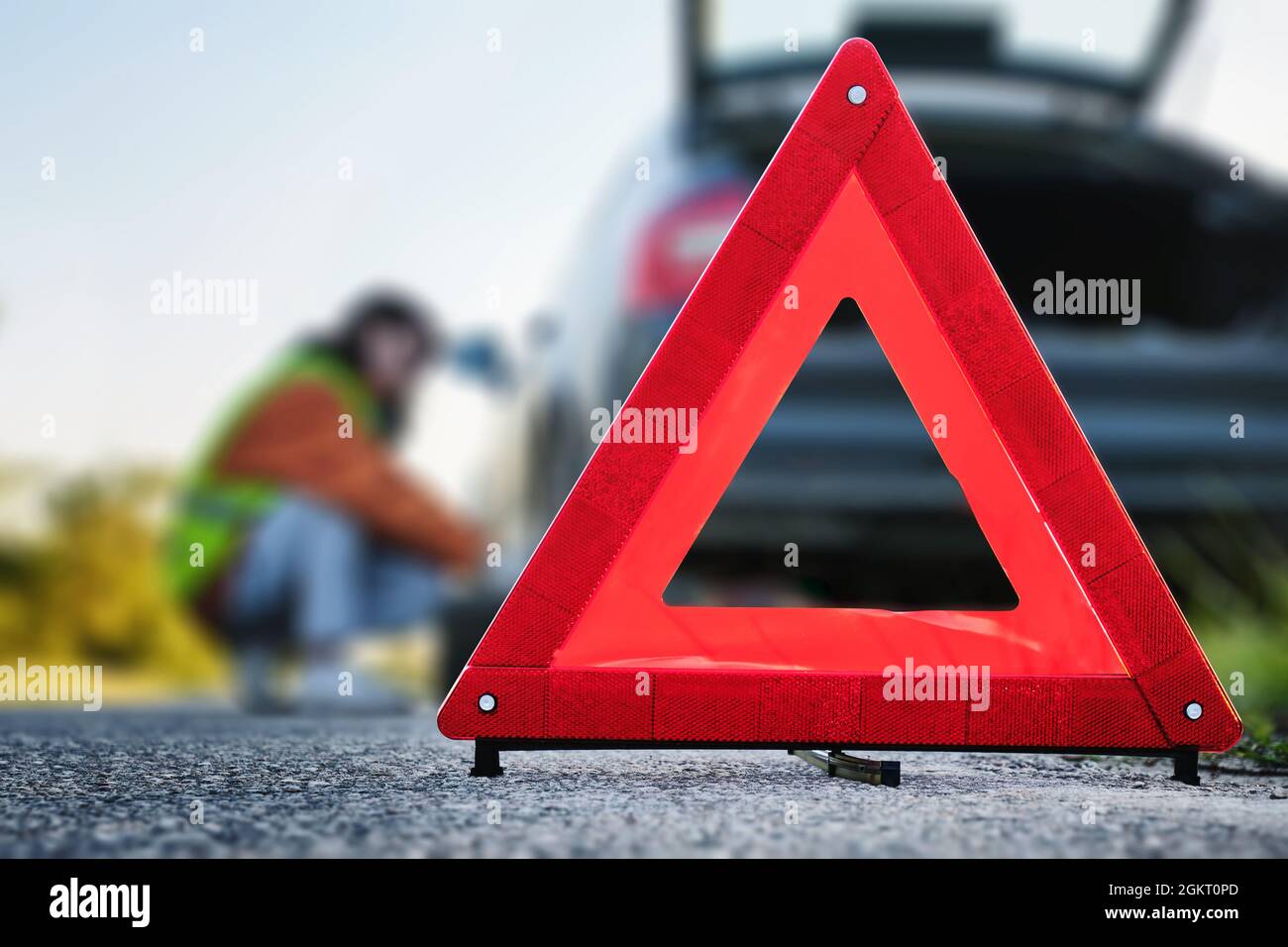 Fold-out warning road sign, driver changes wheel in the background ...