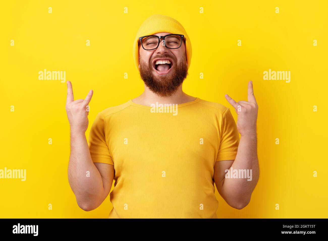 positive man makes rock n roll gesture over yellow background, people ...